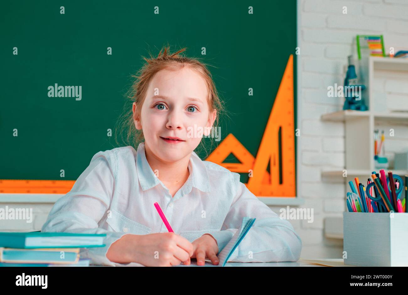Little girl pupil with happy face expression near desk with school ...