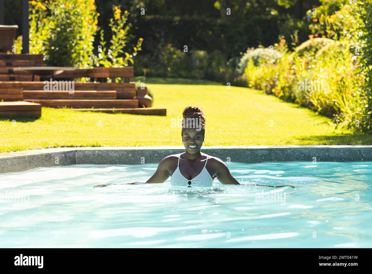 A young African American woman enjoys a swim in a pool at home Stock ...