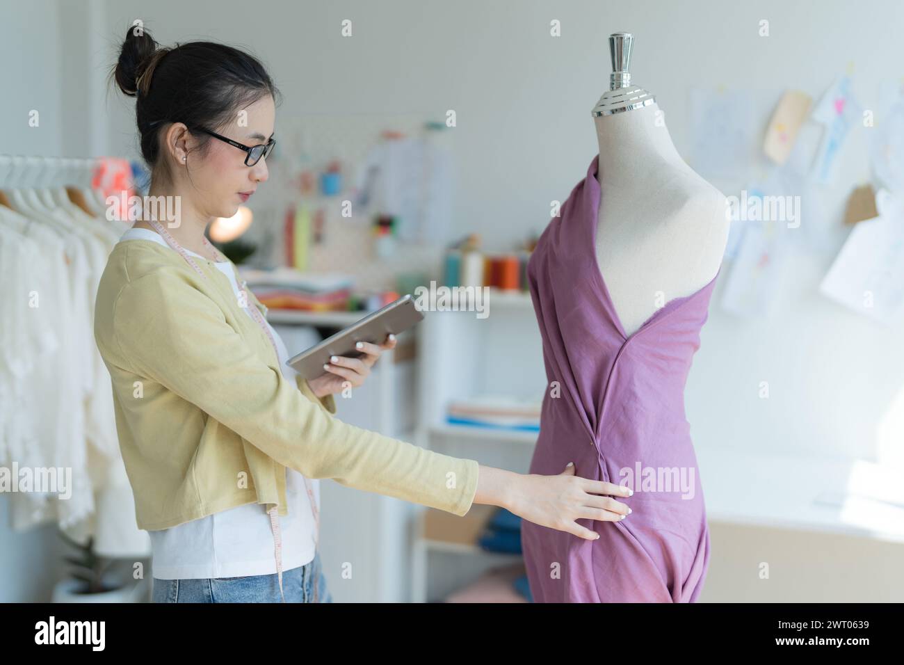 Attractive young fashion designer standing in studio holding tablet ...