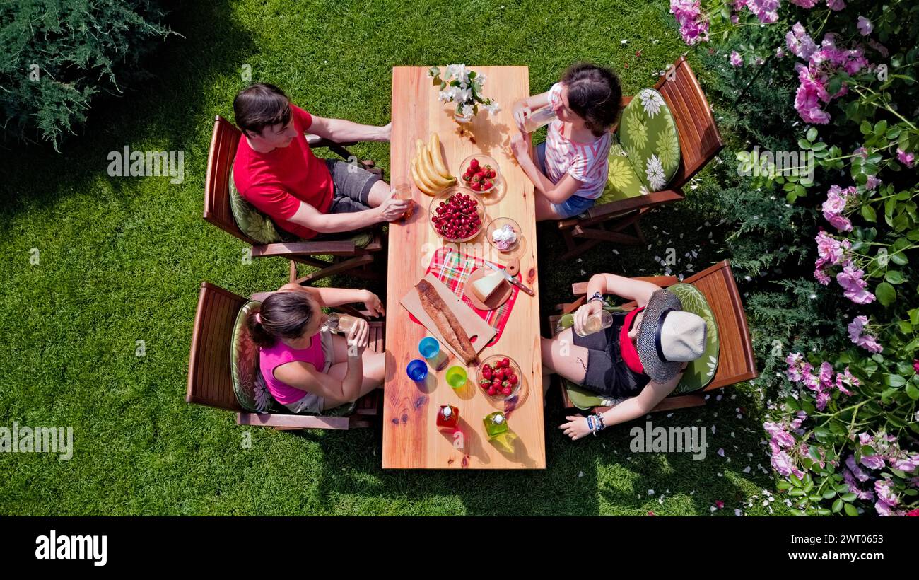 Family and friends eating together outdoors on summer garden party in ...