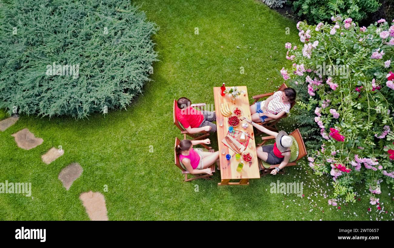 Family and friends eating together outdoors on summer garden party in ...