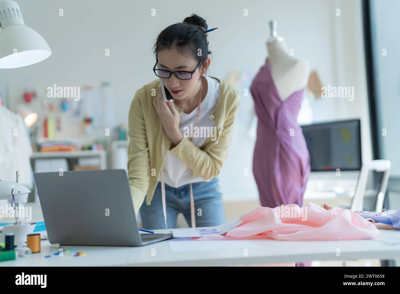 Young fashion designer wearing eyeglasses talking on the phone and ...