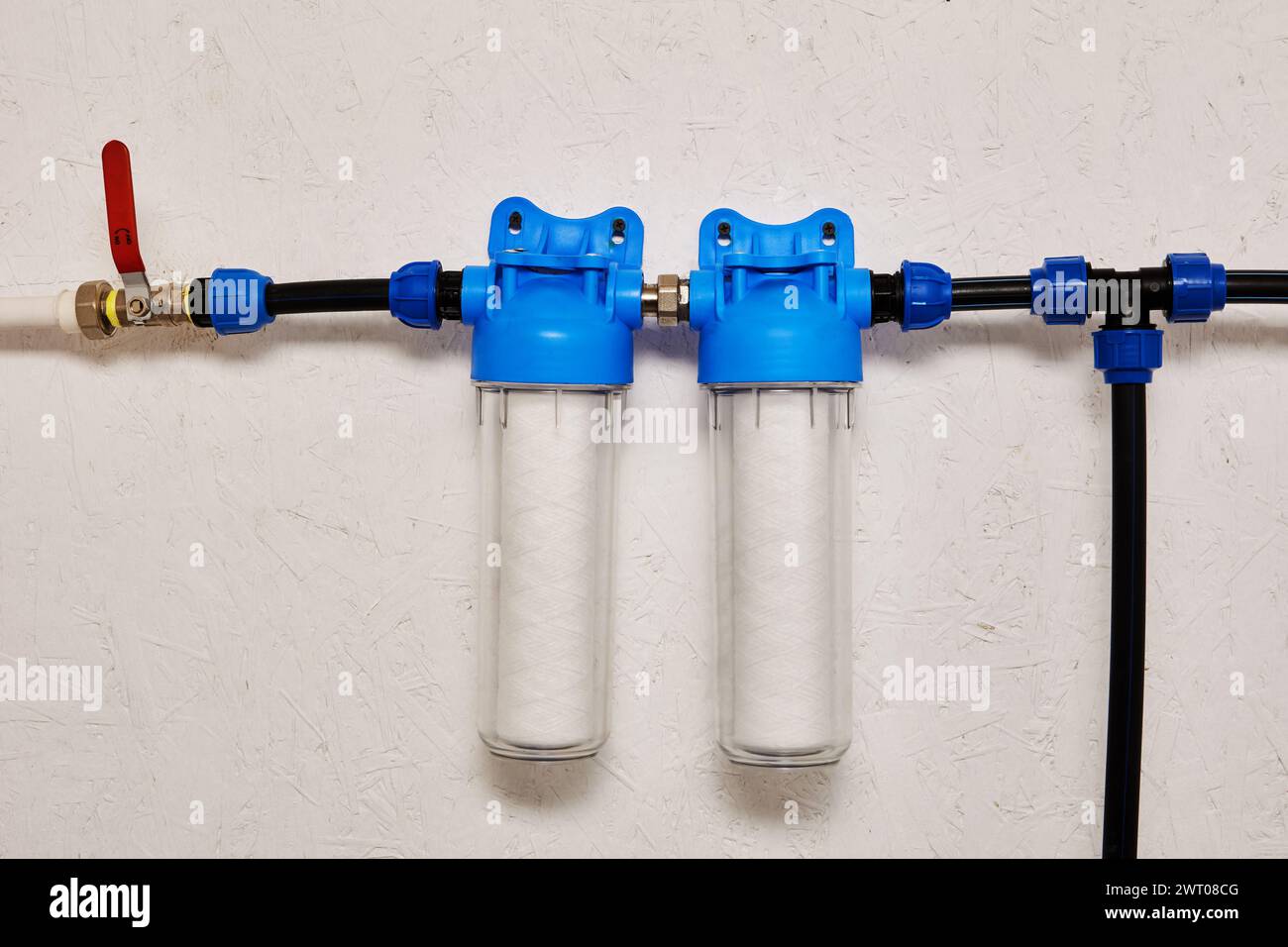 Water filtration system with two clear canisters and blue lids is ...