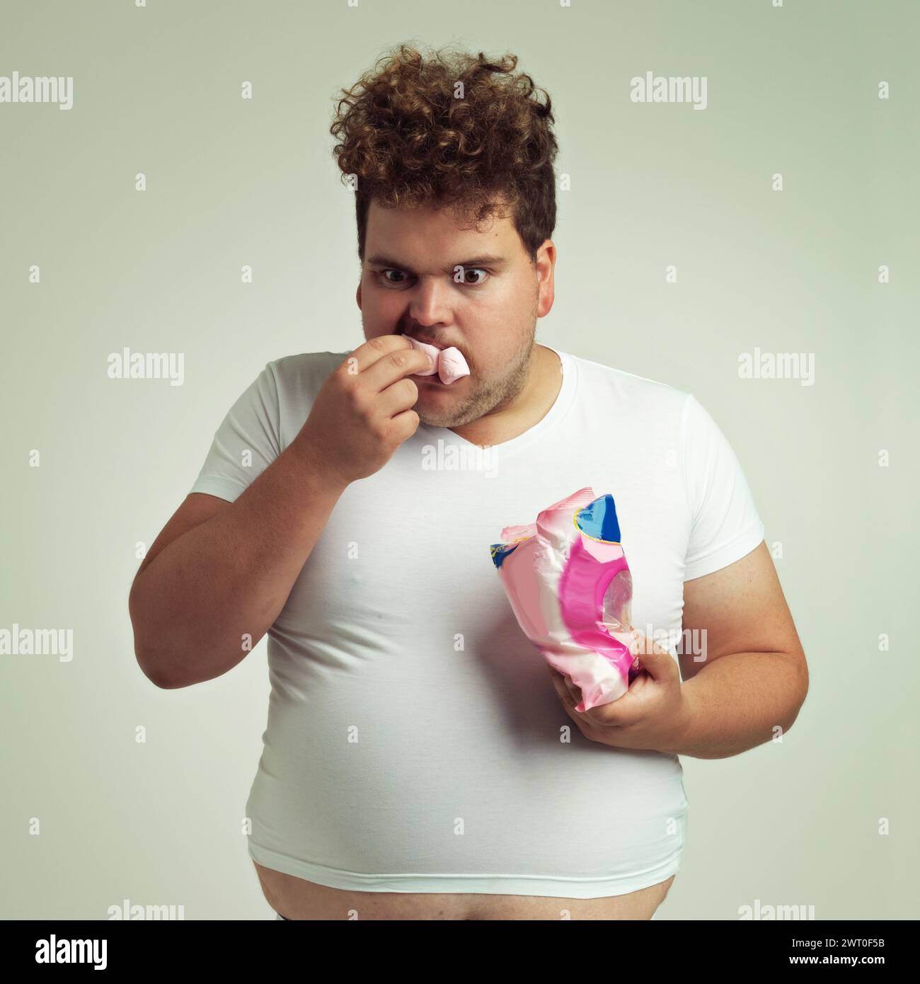 Food, hungry and marshmallow with plus size man in studio on gray ...