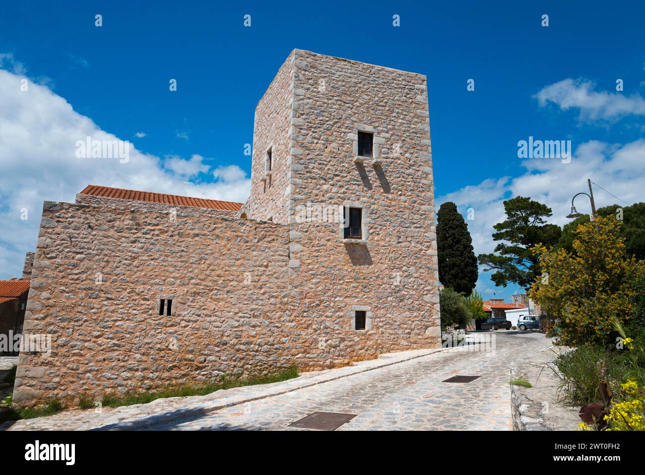 Old stone house under a bright blue sky with scattered clouds next to a ...