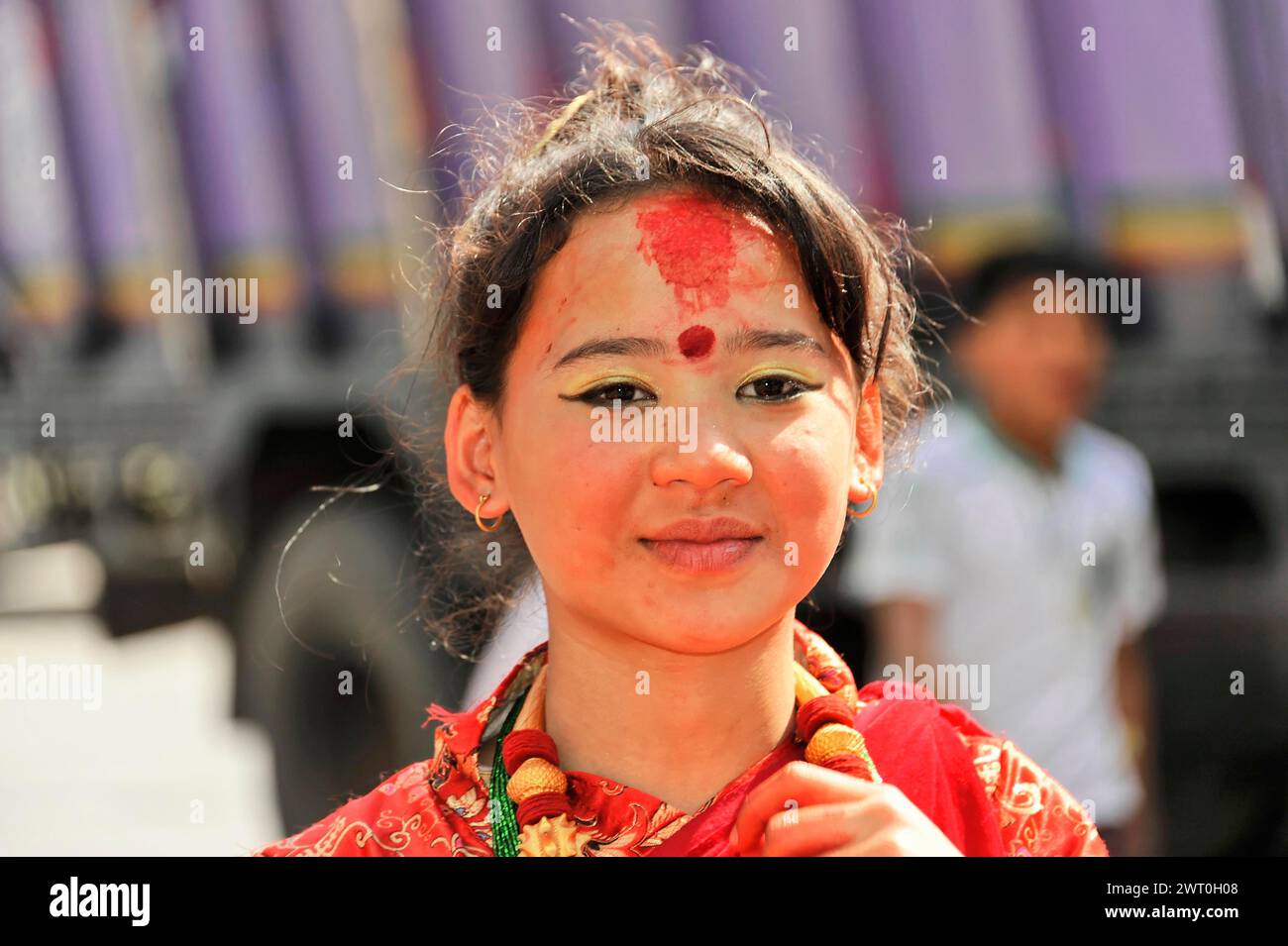 A young girl in traditional dress with a red tika on her forehead ...