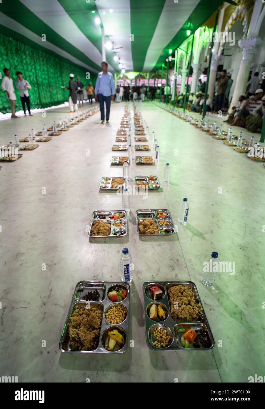 Volunteers distribute and arrange rows of 'iftar' meal for devotees to ...