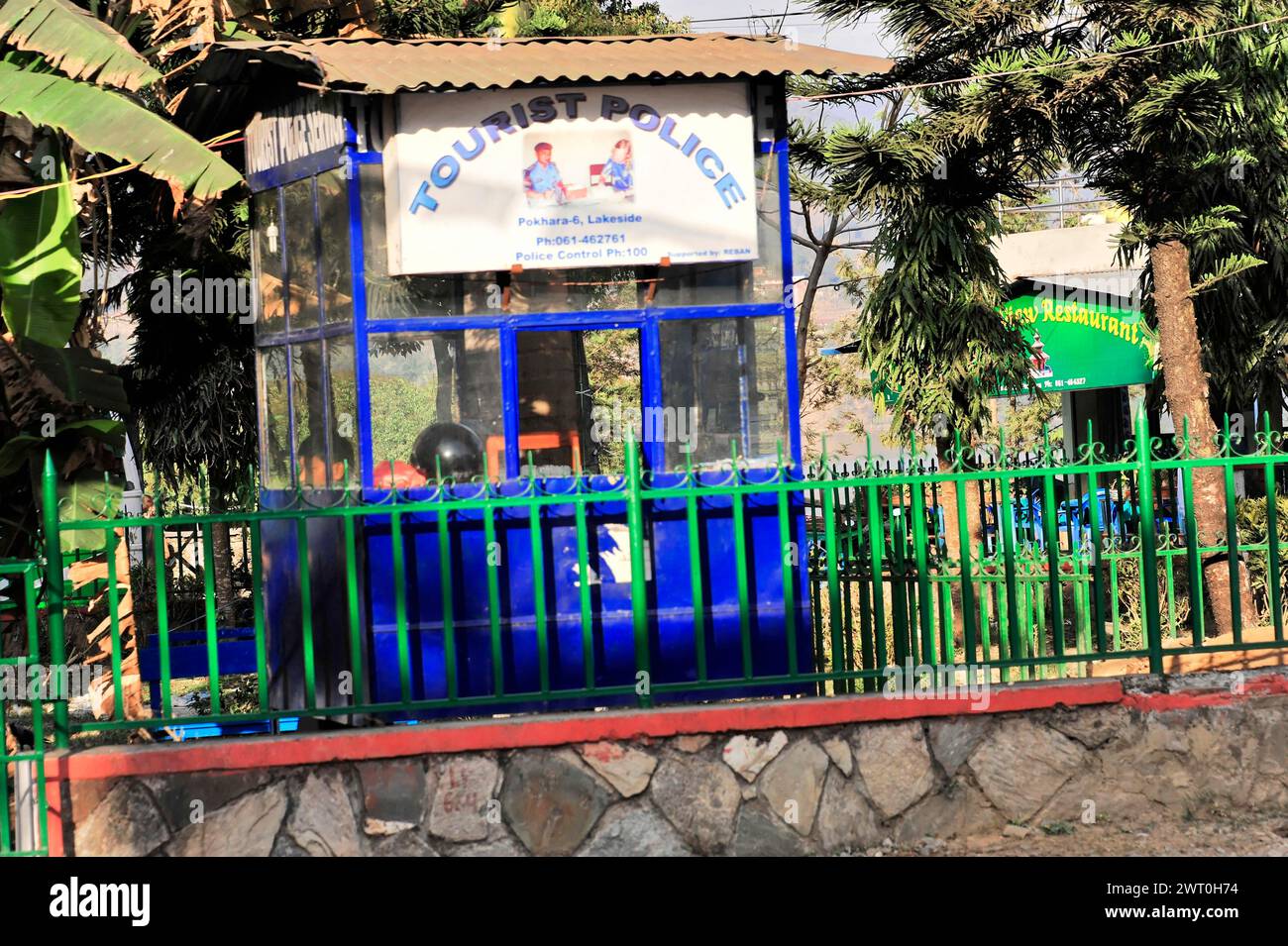 Blue tourist police booth surrounded by green fences and vegetation ...