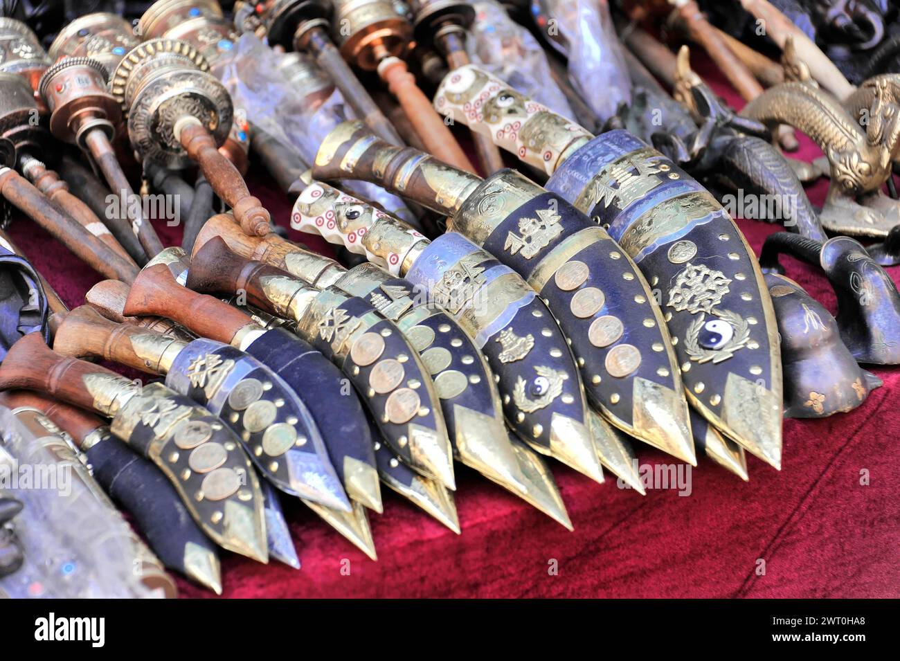 A collection of traditional knife blades laid out on a red cloth ...