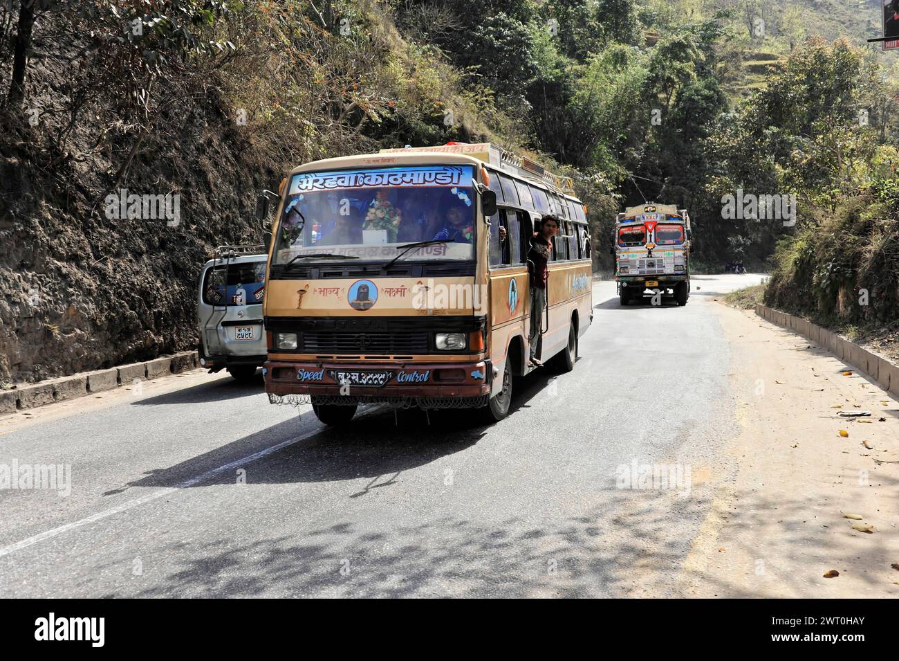 A bus drives on a road in rural surroundings, passengers on board ...