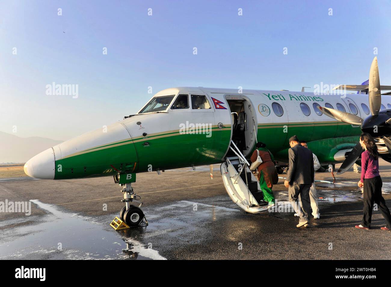 Passengers board a Yeti Airlines propeller plane on an airport tarmac ...