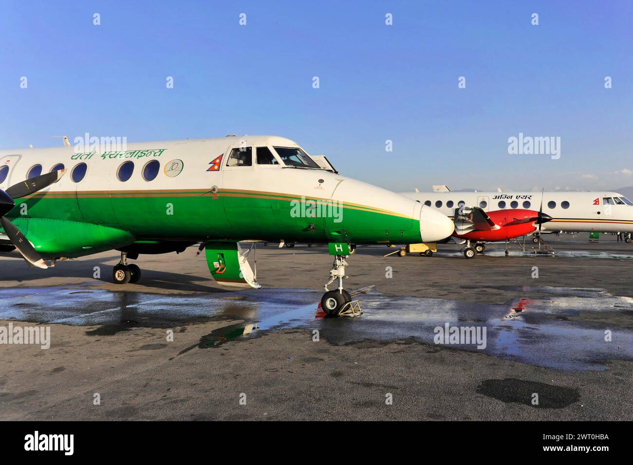 A green and white propeller plane parked on the tarmac in the morning ...