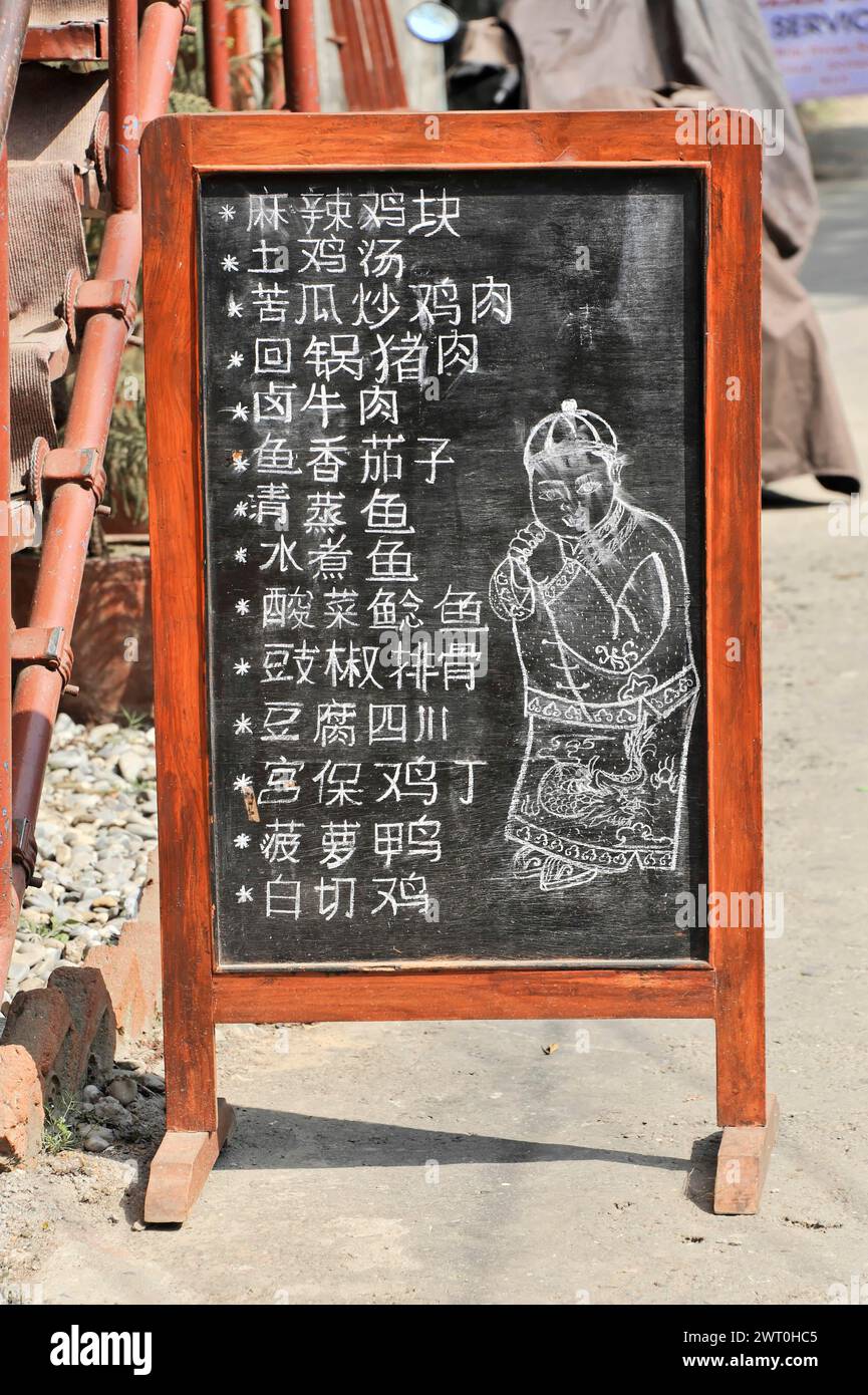 A chalkboard with Chinese characters and a drawing by the road, Pokhara ...