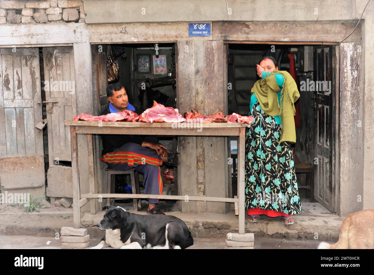 Butcher stall with resting dog and pieces of meat in a market alley ...