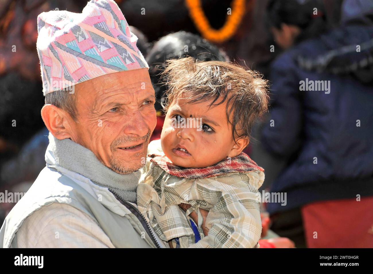 An elderly man holding a child, both in traditional clothing, Kathmandu ...