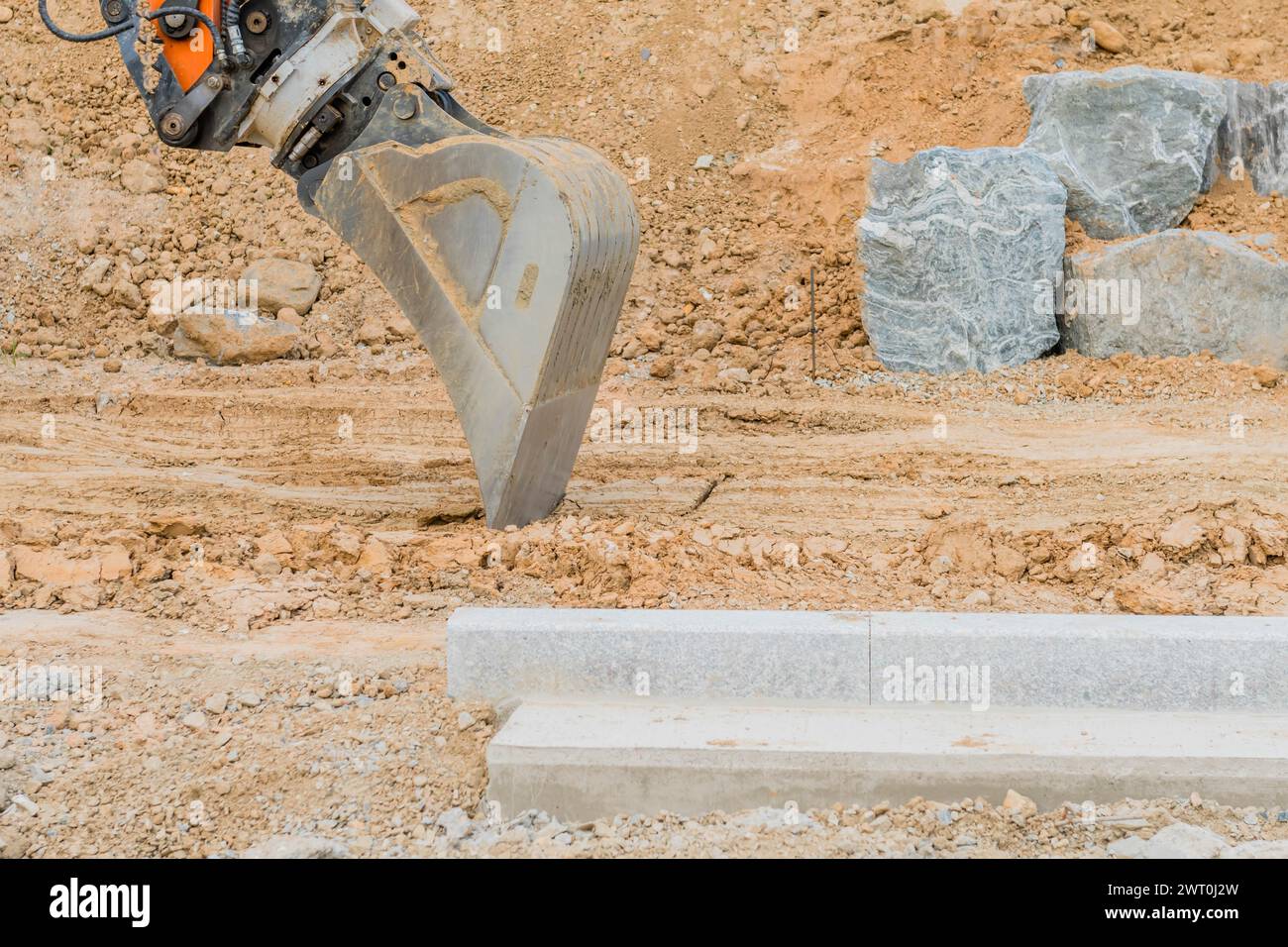 Shovel attached to backhoe arm resting on dirt road at construction ...