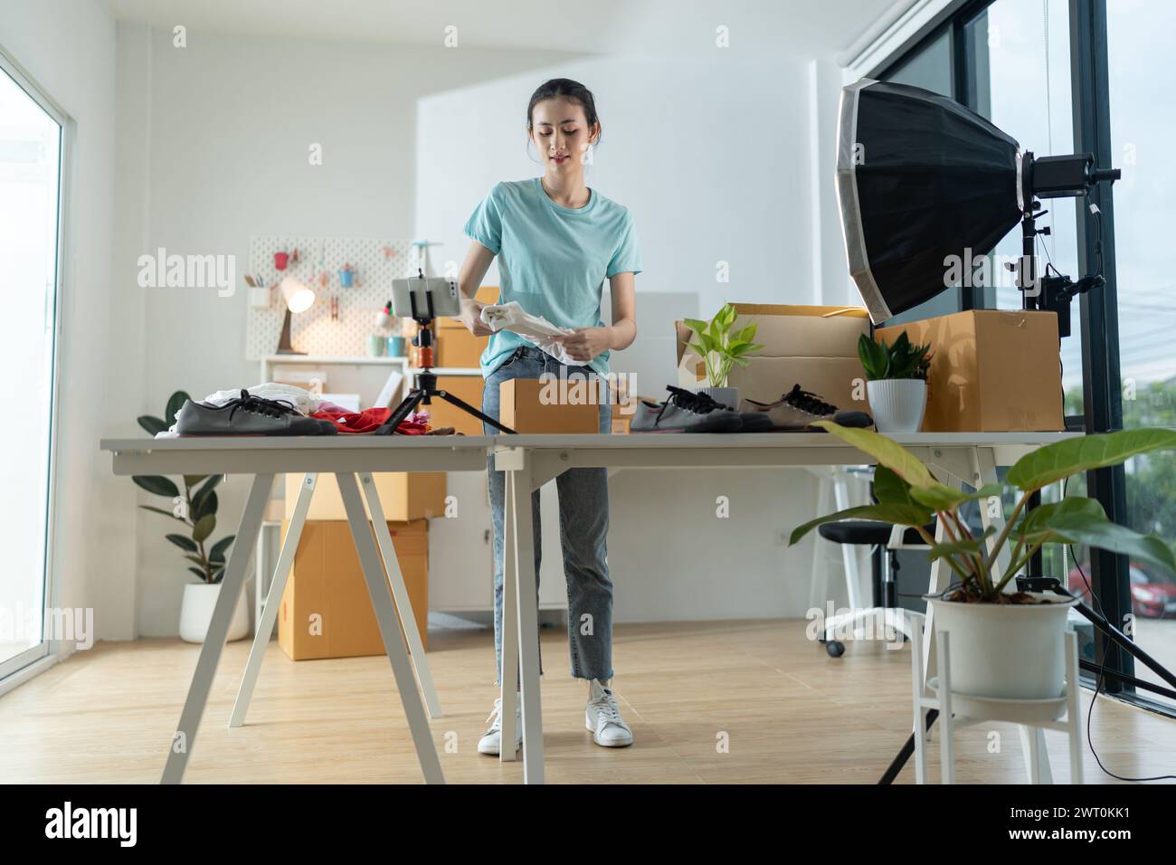 A young woman owner of a small e-commerce business is packing items ...