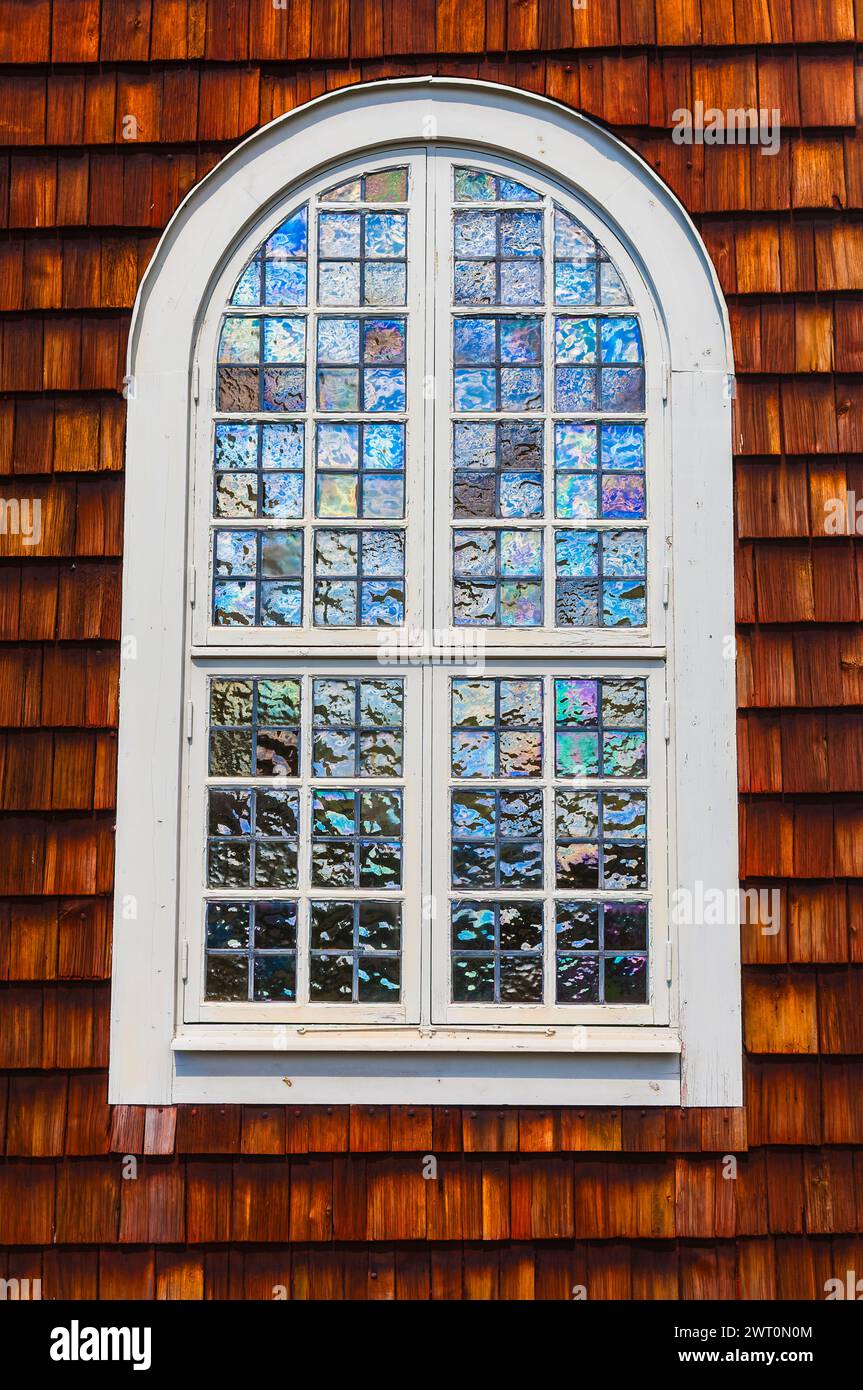 A window set in a wooden wall with a clean white frame, showcasing a ...
