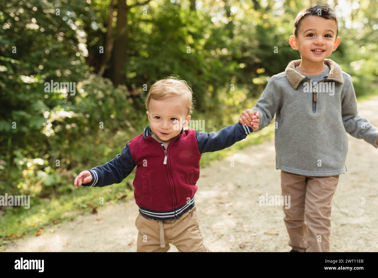 Two happy kids on a walk together on a forest path holding hands Stock ...