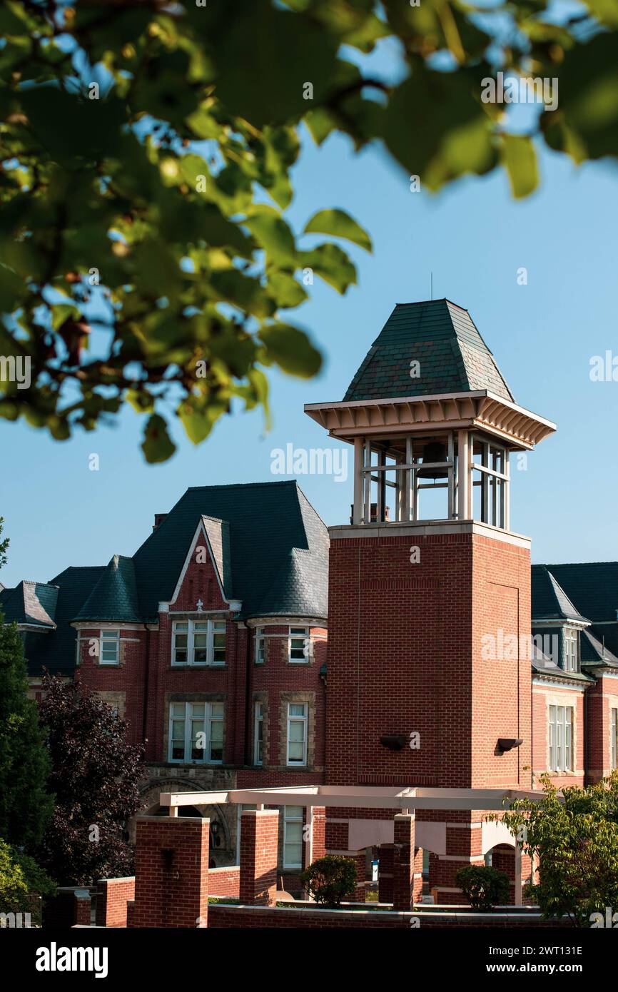 Red brick bell tower framed by tree leaves on a clear blue sky Stock ...