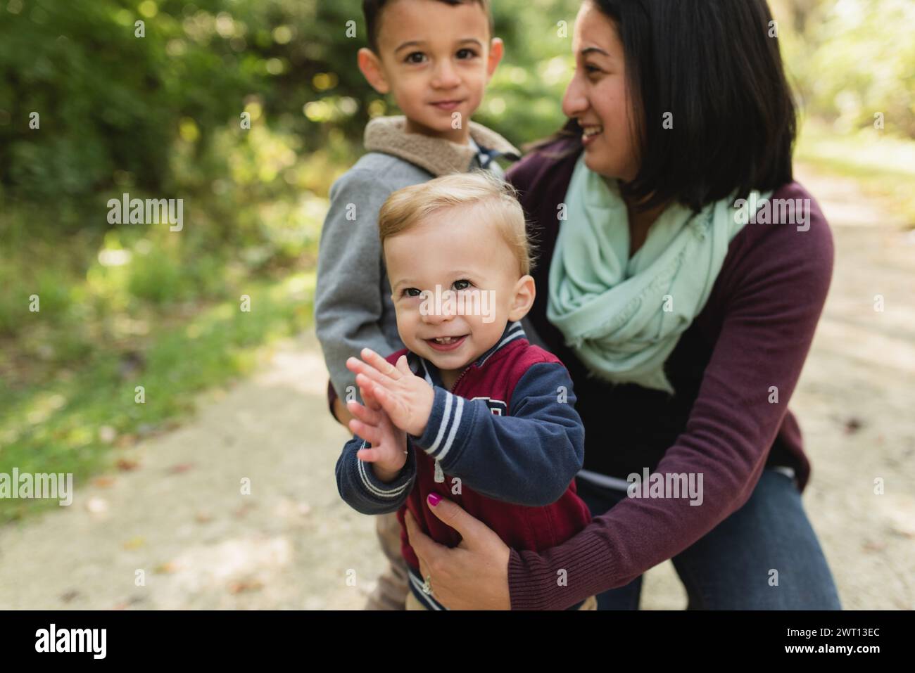 Happy boy clapping while smiling mother holds her toddler sons Stock ...