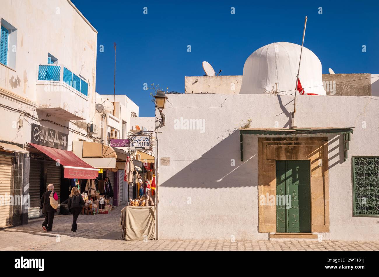 A traditional white domed building with a decorated door and shops in the ancient medina of ...