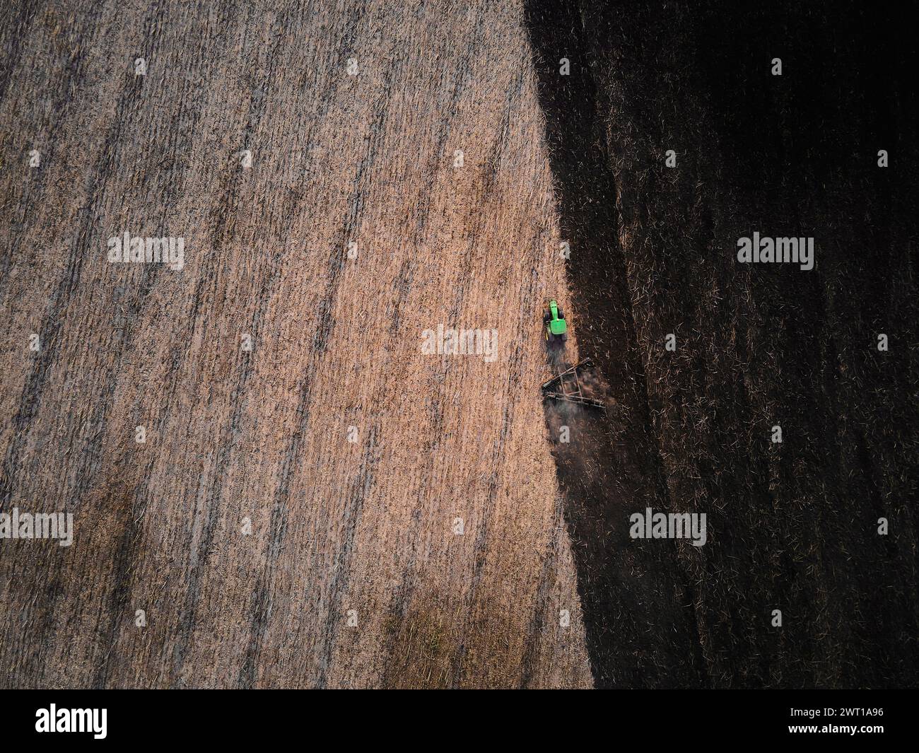 Tractor cultivating vast farmland, creating a contrast between tilled ...