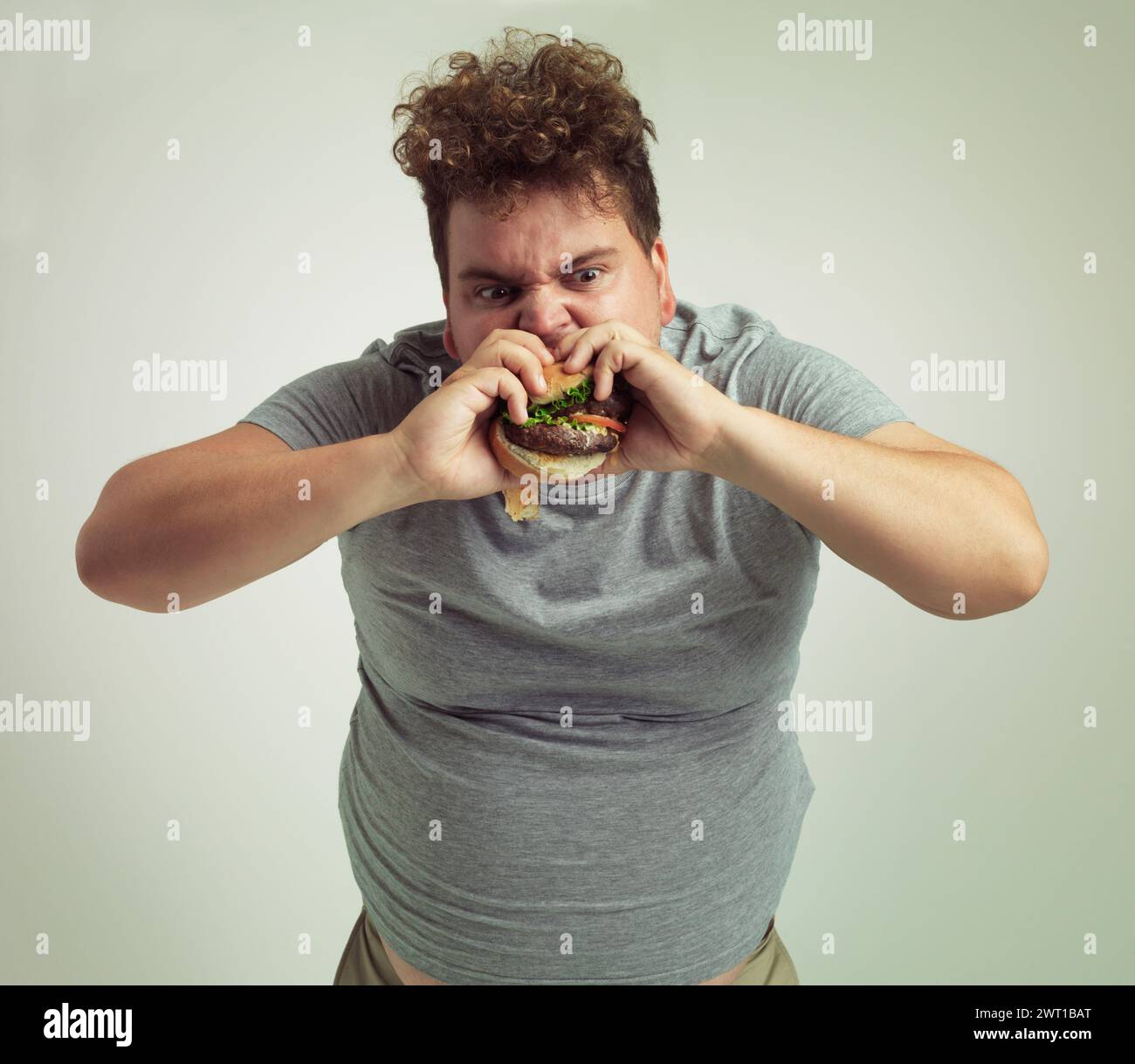 Takeaway, weight gain and burger for man in studio with fastfood for ...