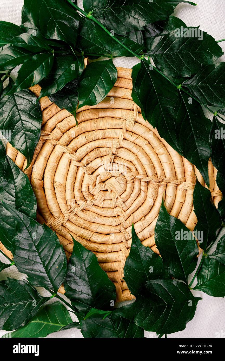 A woven rattan heart centerpiece enclosed by vibrant green leaves, top ...