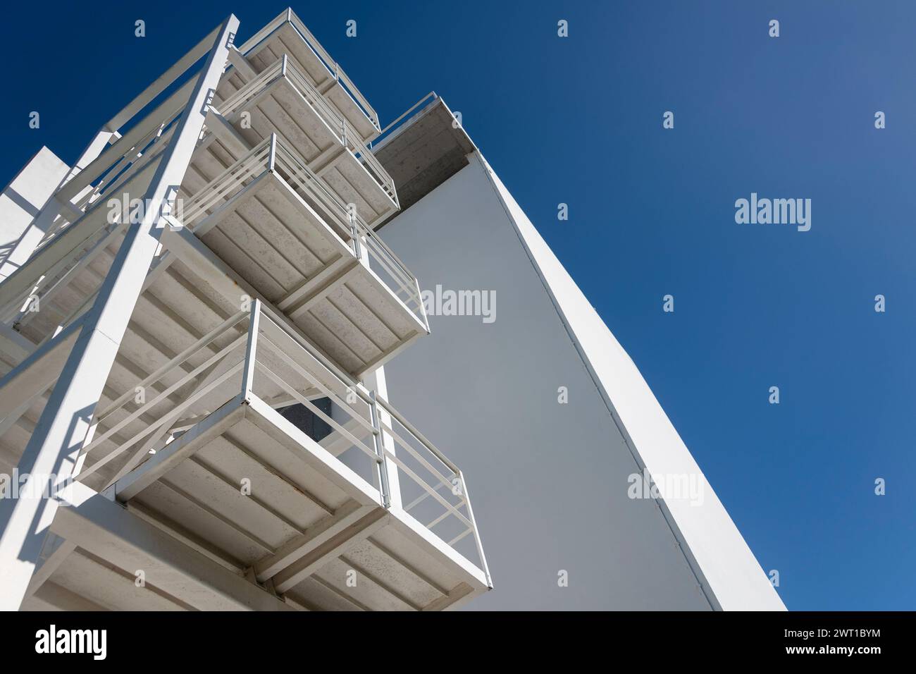 modern white concrete building with external metal fire escape stairs ...