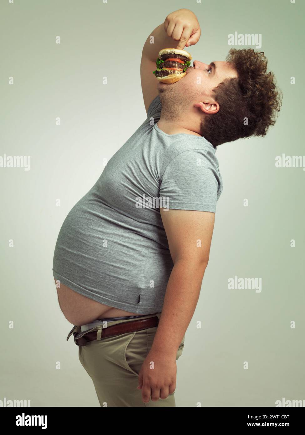 Fast food, hungry and man with hamburger in studio background with ...