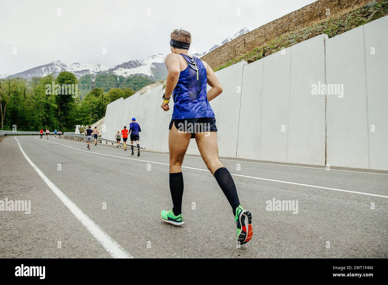 male athlete running last in group runners in mountain marathon race ...