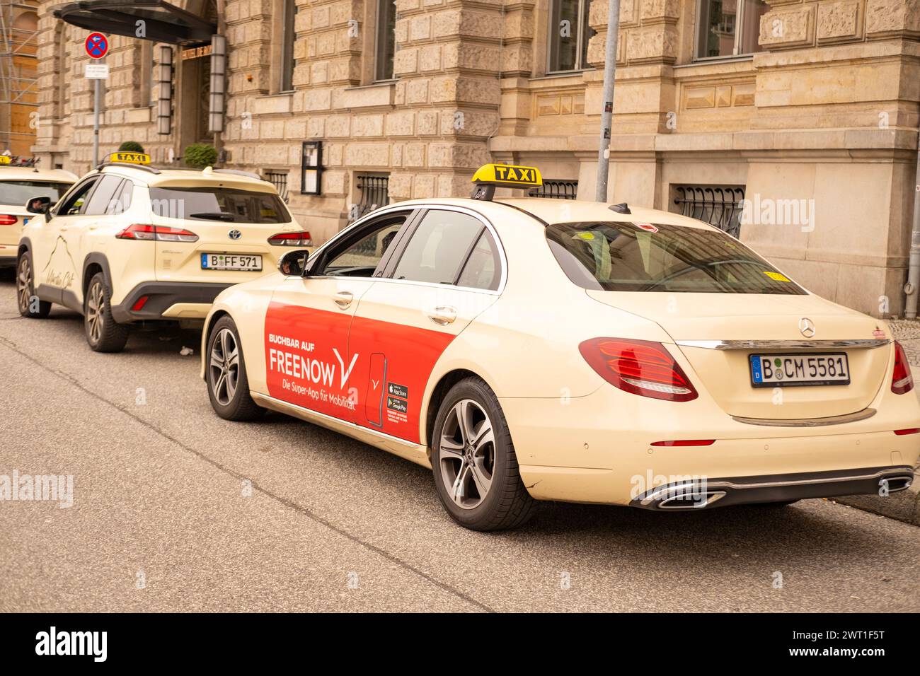 yellow Mercedes-Benz taxi with taxi company logos car on street of ...