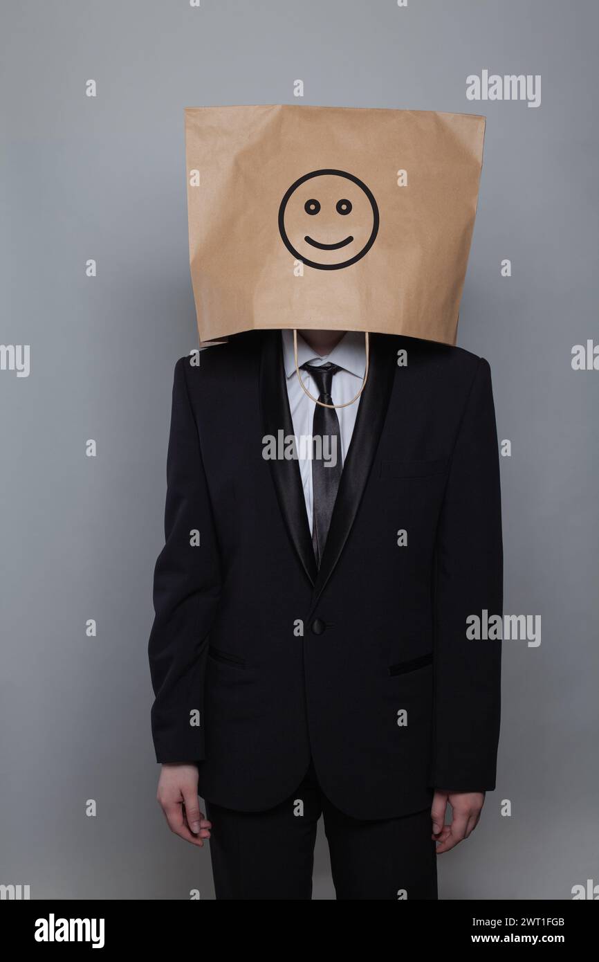 Anonymous businessman hiding his head behind happy smile emoticon on ...