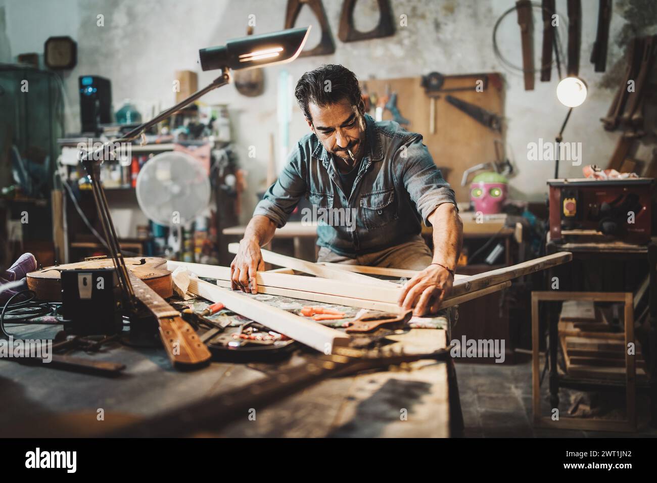 Focused craftsman measuring wood in his workshop, surrounded by tools ...