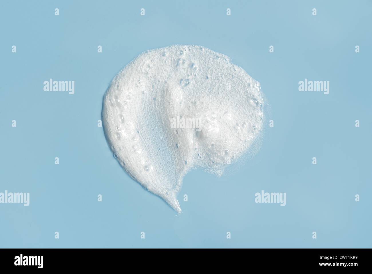 Face cleansing mousse sample. White cleanser foam bubbles on blue ...