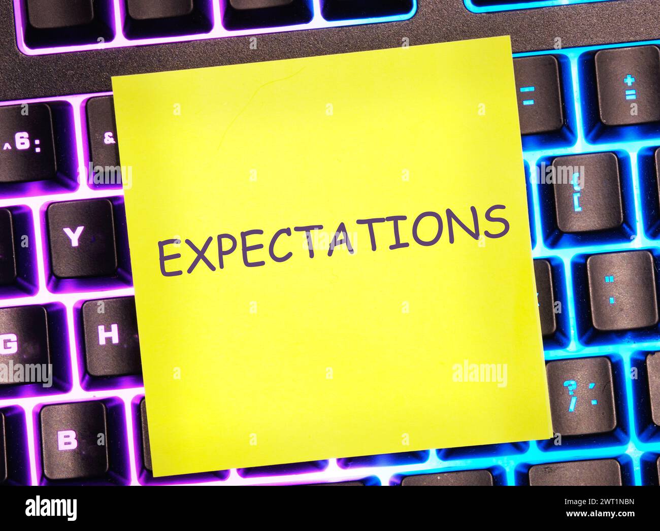 Word Expectations written on a yellow sticker on a colored backlit ...