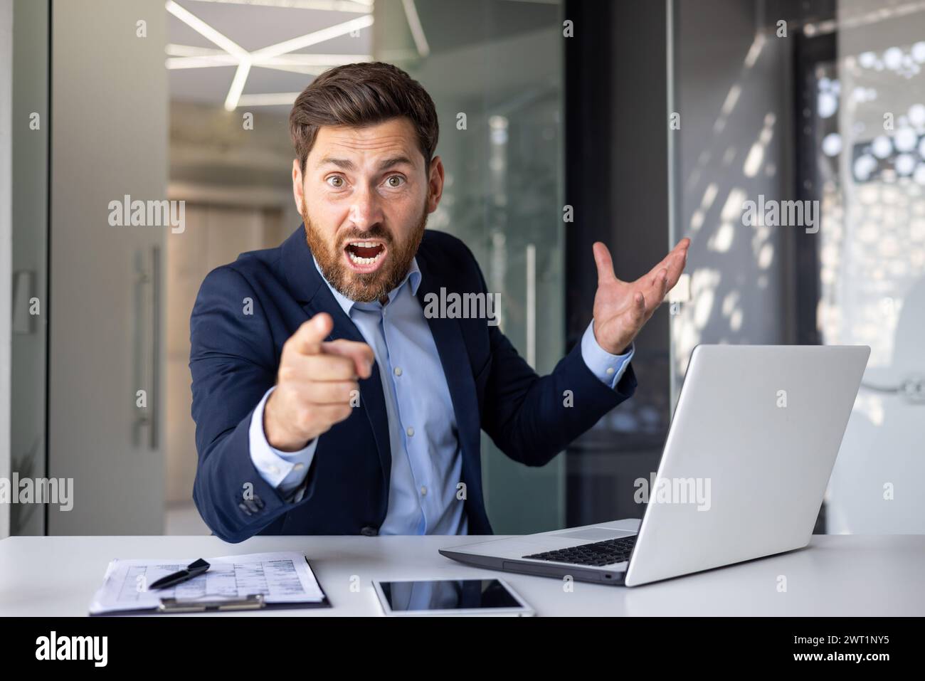 Angry young man businessman sitting in the office at the table and ...