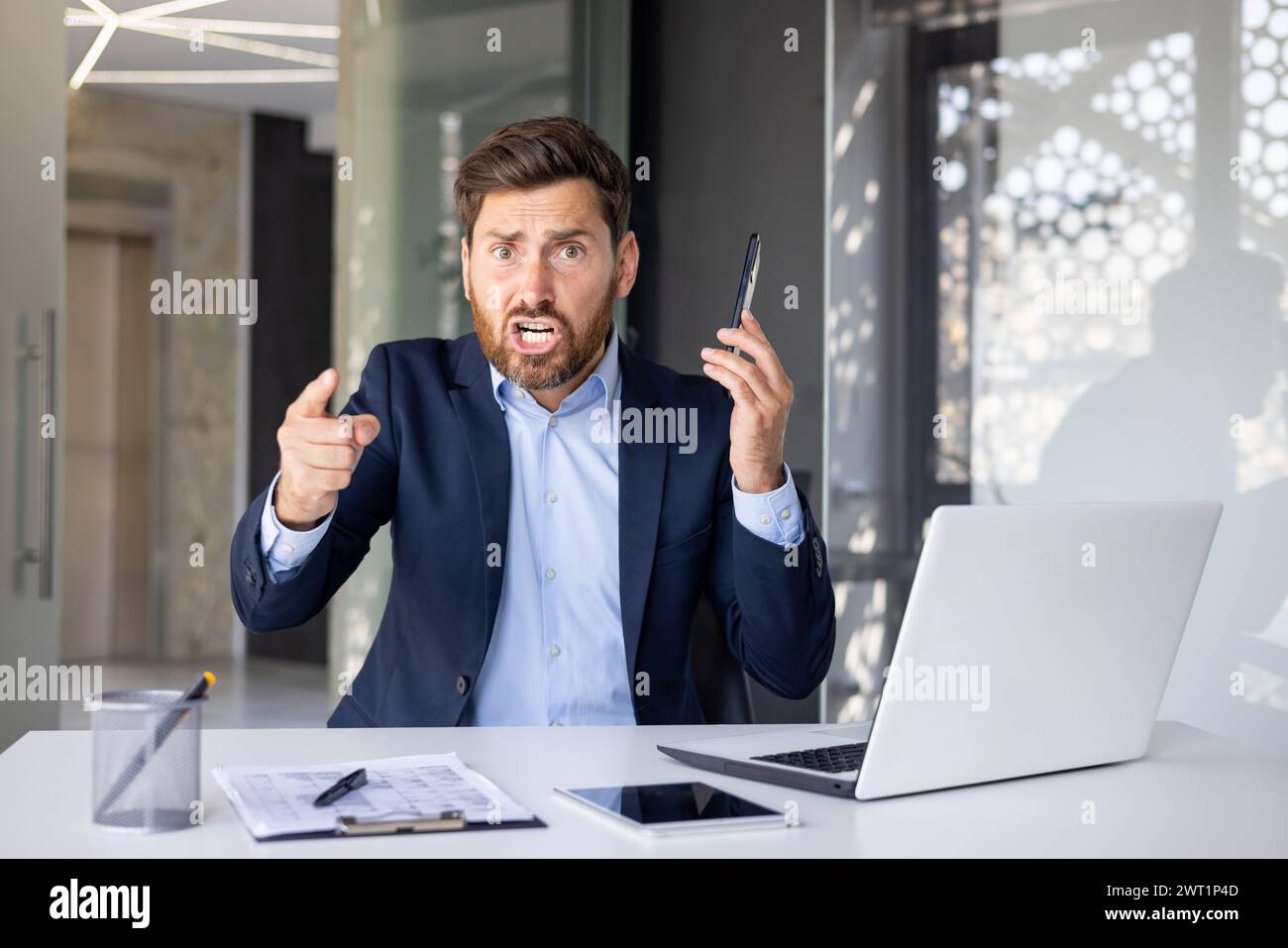 Portrait of an angry young man businessman sitting in the office at the ...