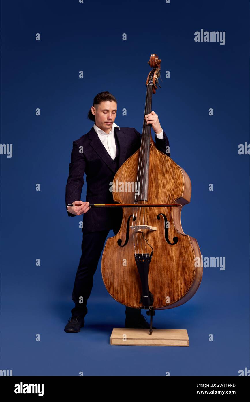 Stylish man in suit paying double bass, making classical music live ...
