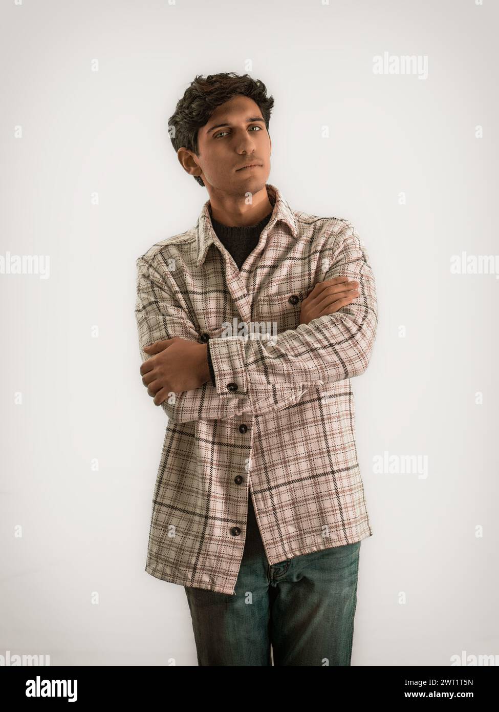 A man with folded arms standing confidently, displaying a posture of ...