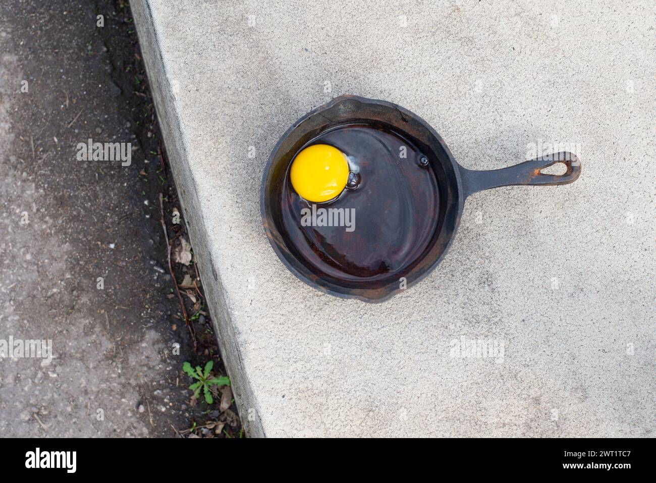 Raw egg in a frying pan on the hot asphalt road, fried food on the ...