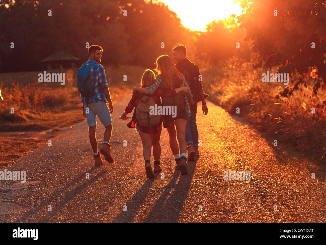 Group of four friends having fun hiking through countryside together on ...