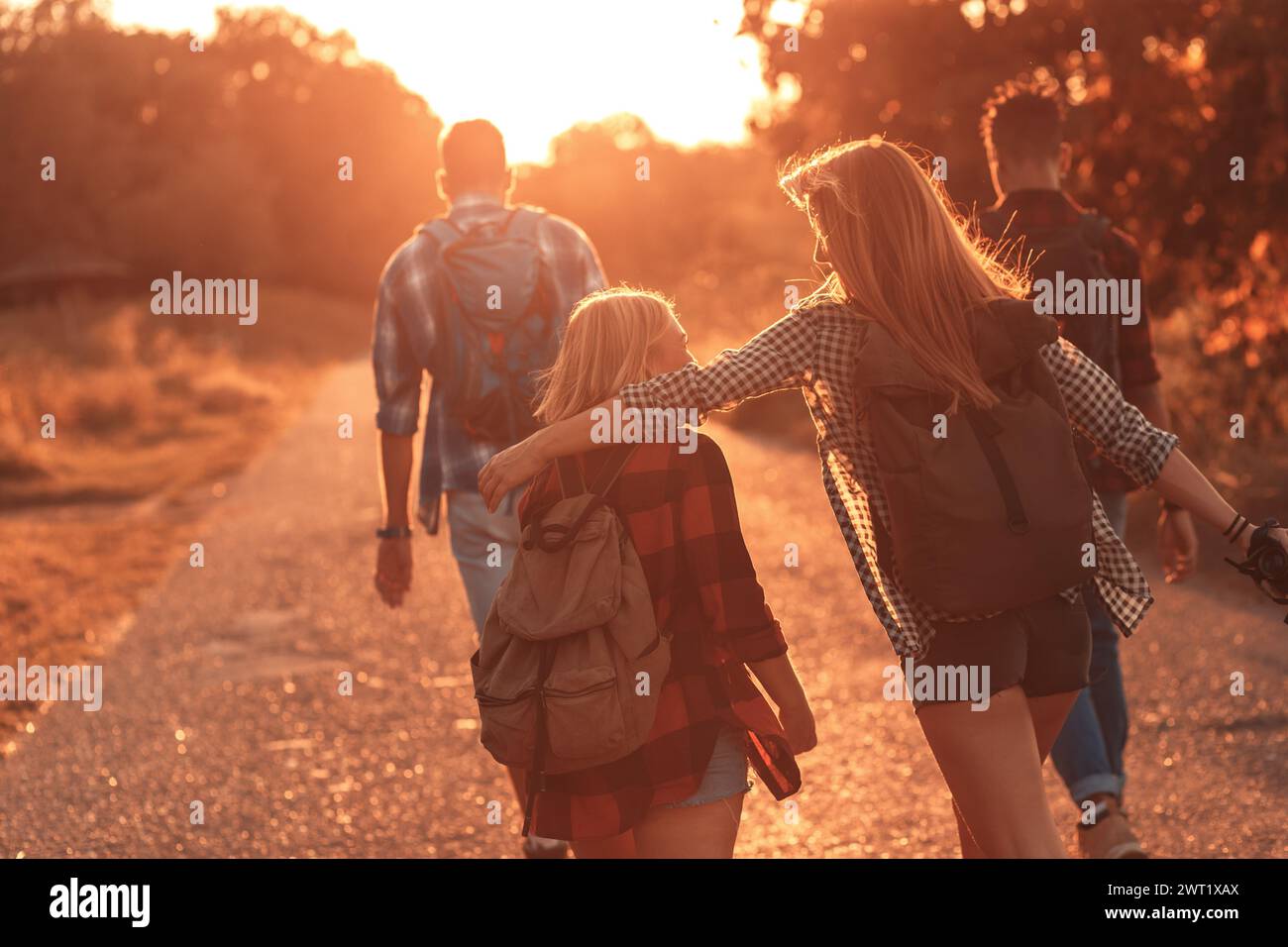 Group of four friends having fun hiking through countryside together on ...