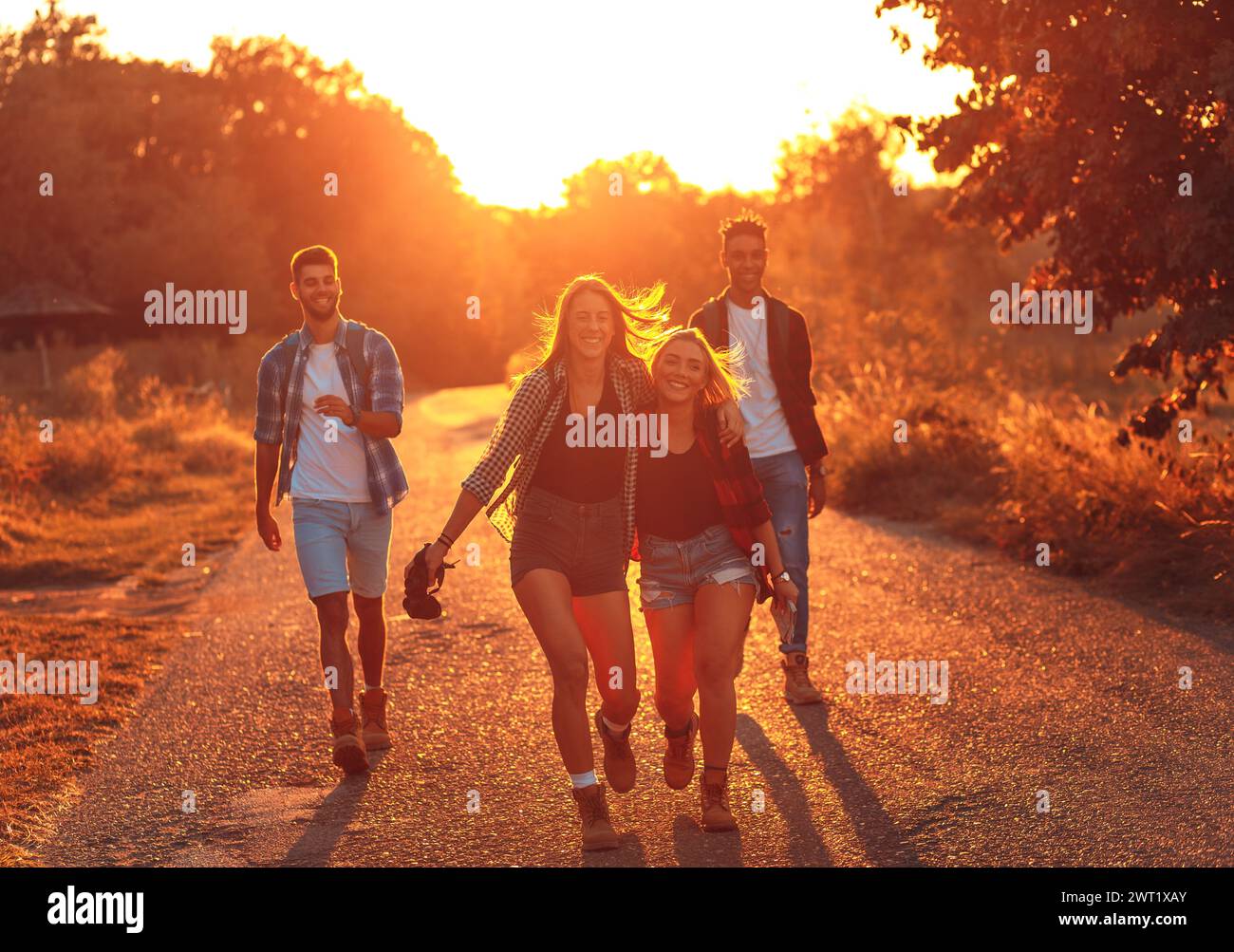 Group of four friends having fun hiking through countryside together on ...