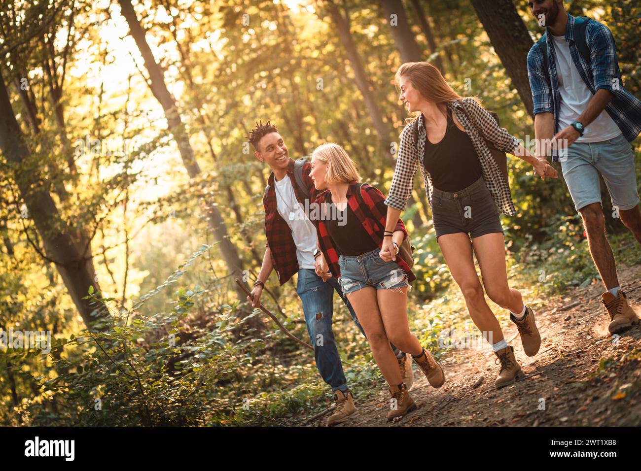 Group of four friends having fun hiking through forest together Stock ...