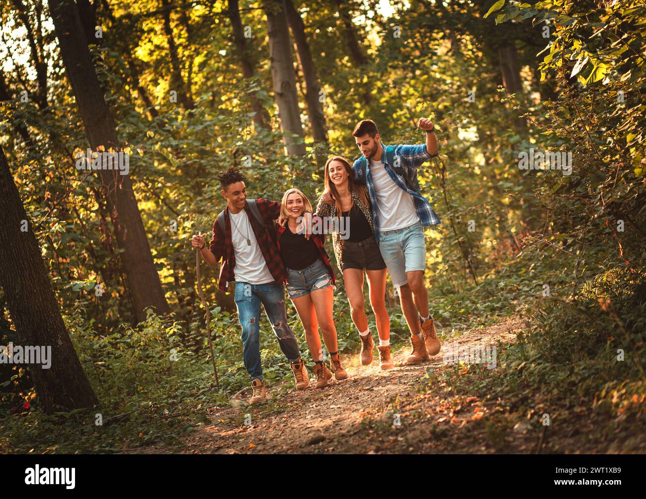 Group of four friends having fun hiking through forest together Stock ...