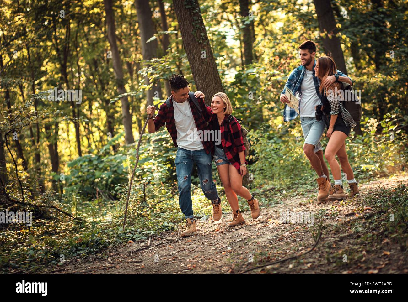 Group of four friends having fun hiking through forest together Stock ...