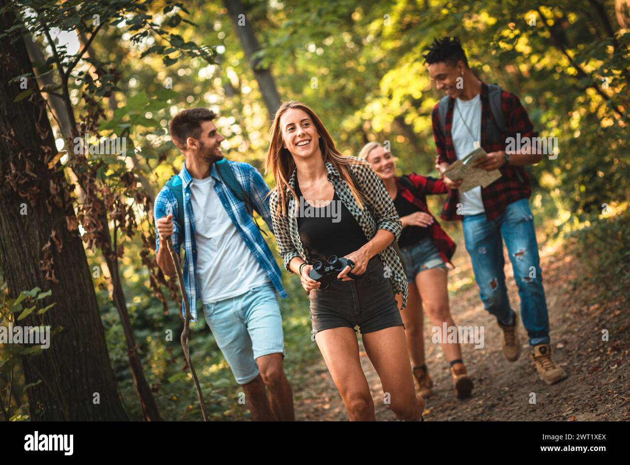 Group of four friends having fun hiking through forest together Stock ...