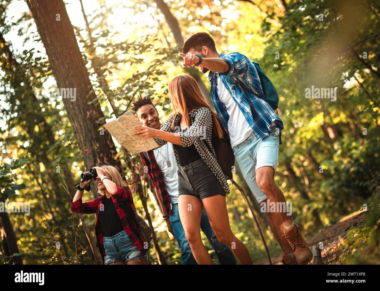 Group of four friends having fun hiking through forest together Stock ...